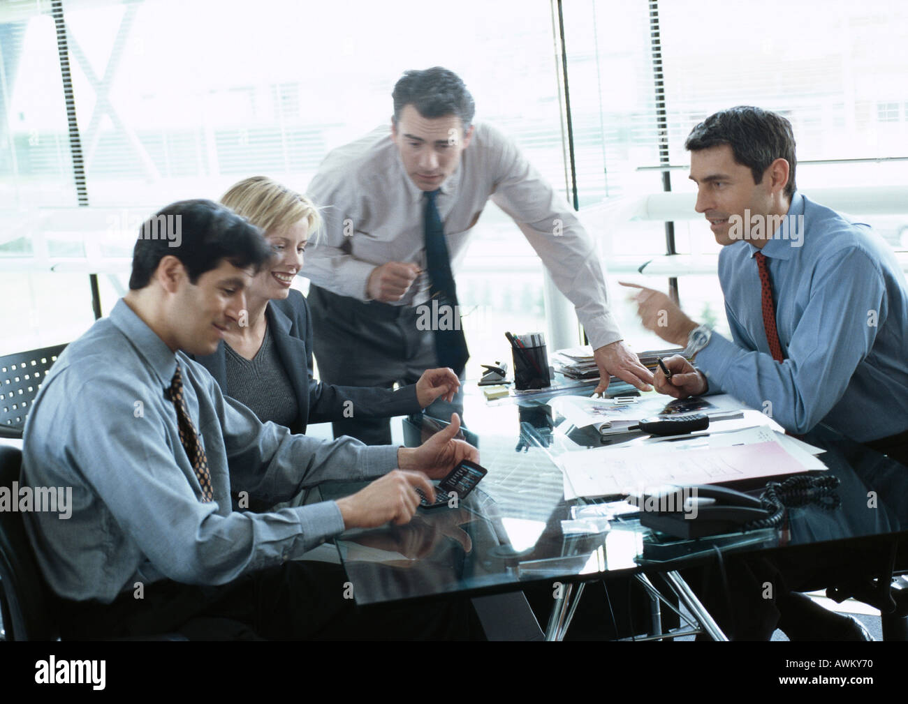 Business associates working together at desk, one using calculator ...