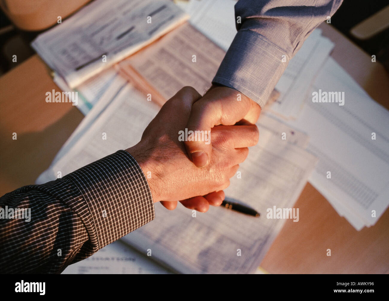 Handshake above documents on table Stock Photo - Alamy