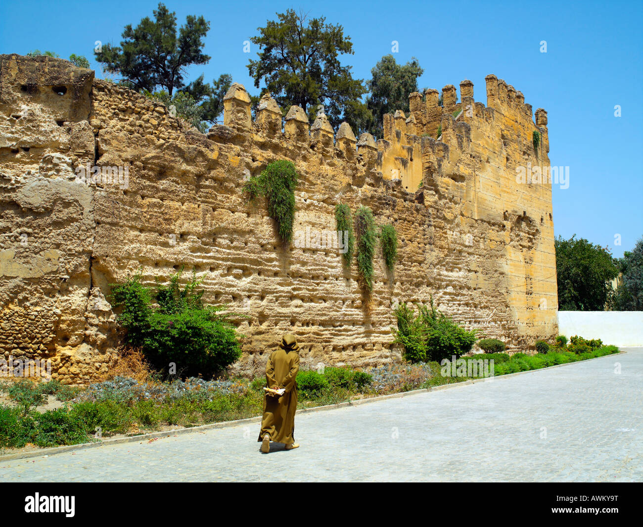 Man wearing the traditional Jellaba walking by the walls of Fez Jdid ...