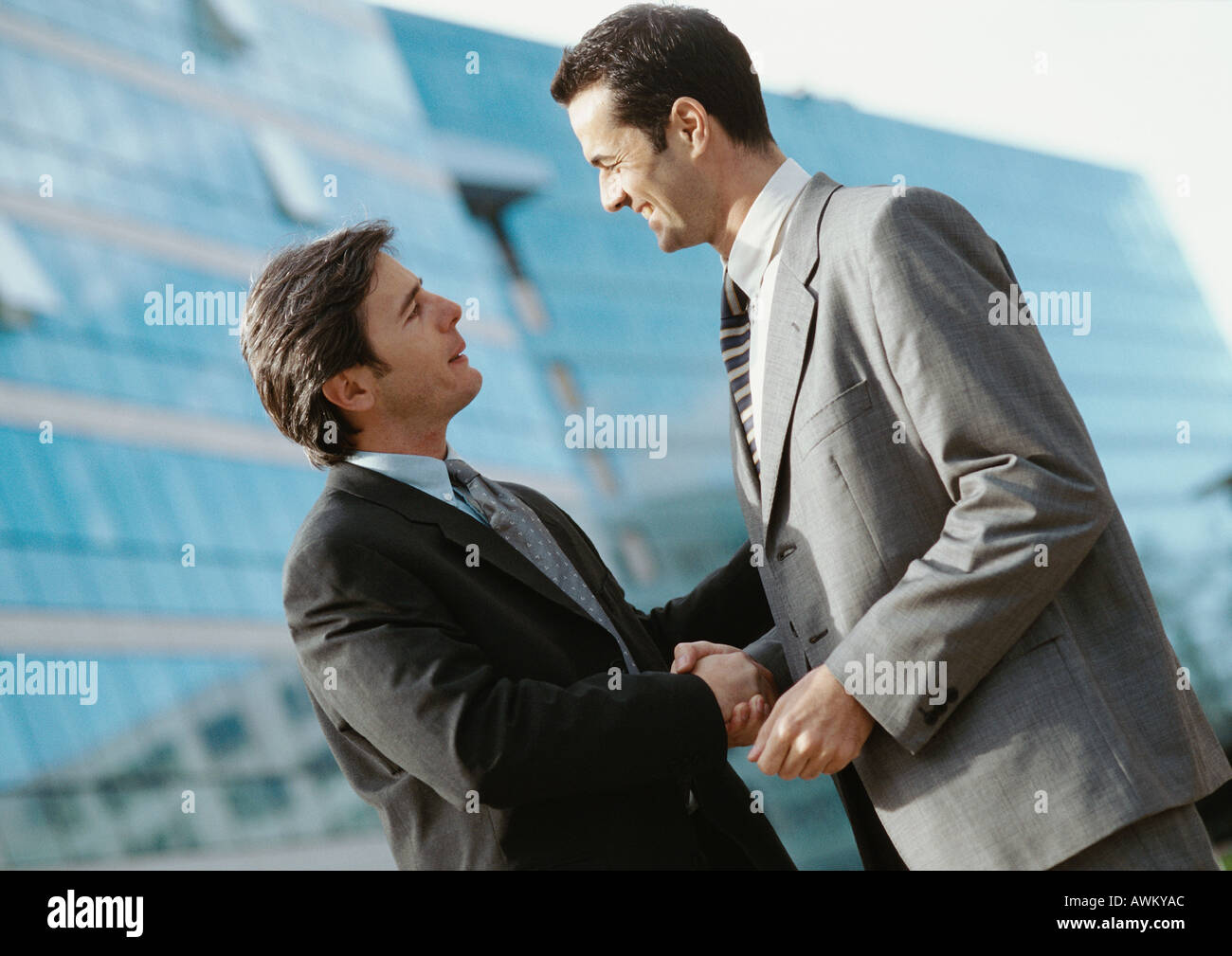 Two businessmen shaking hands, buildings in background Stock Photo - Alamy