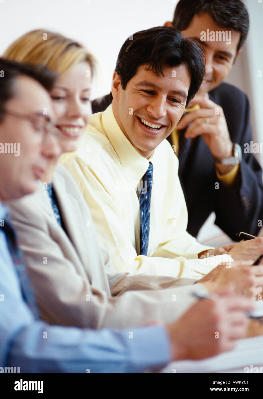 Business people sitting side by side at a table, smiling Stock Photo ...