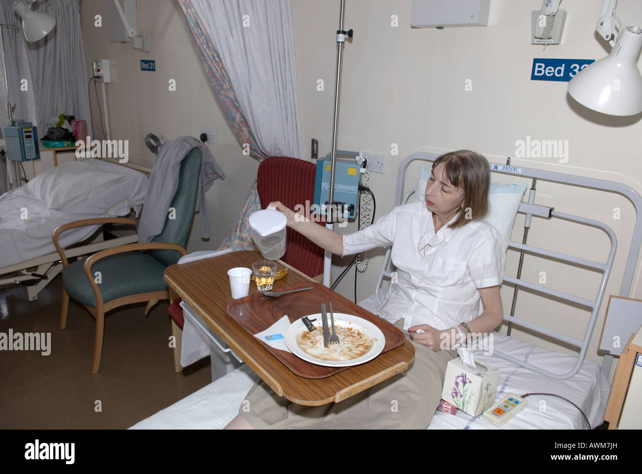 Female patient pouring water into a glass in hospital whilst on ...