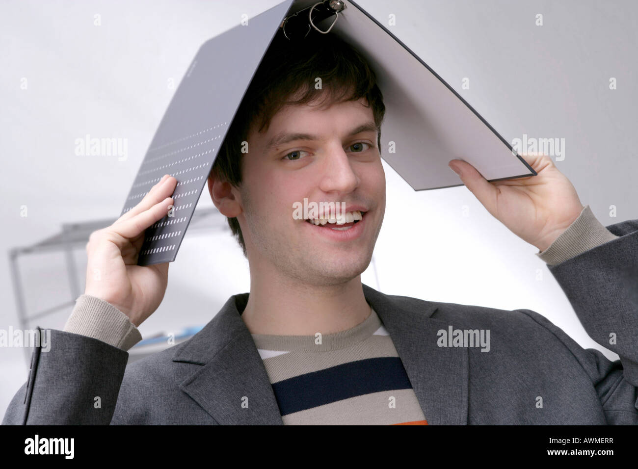 Young man holding a binder over his head, smiling Stock Photo - Alamy