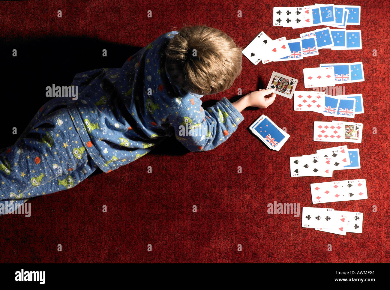 boy laying down and playing cards by himself Stock Photo - Alamy