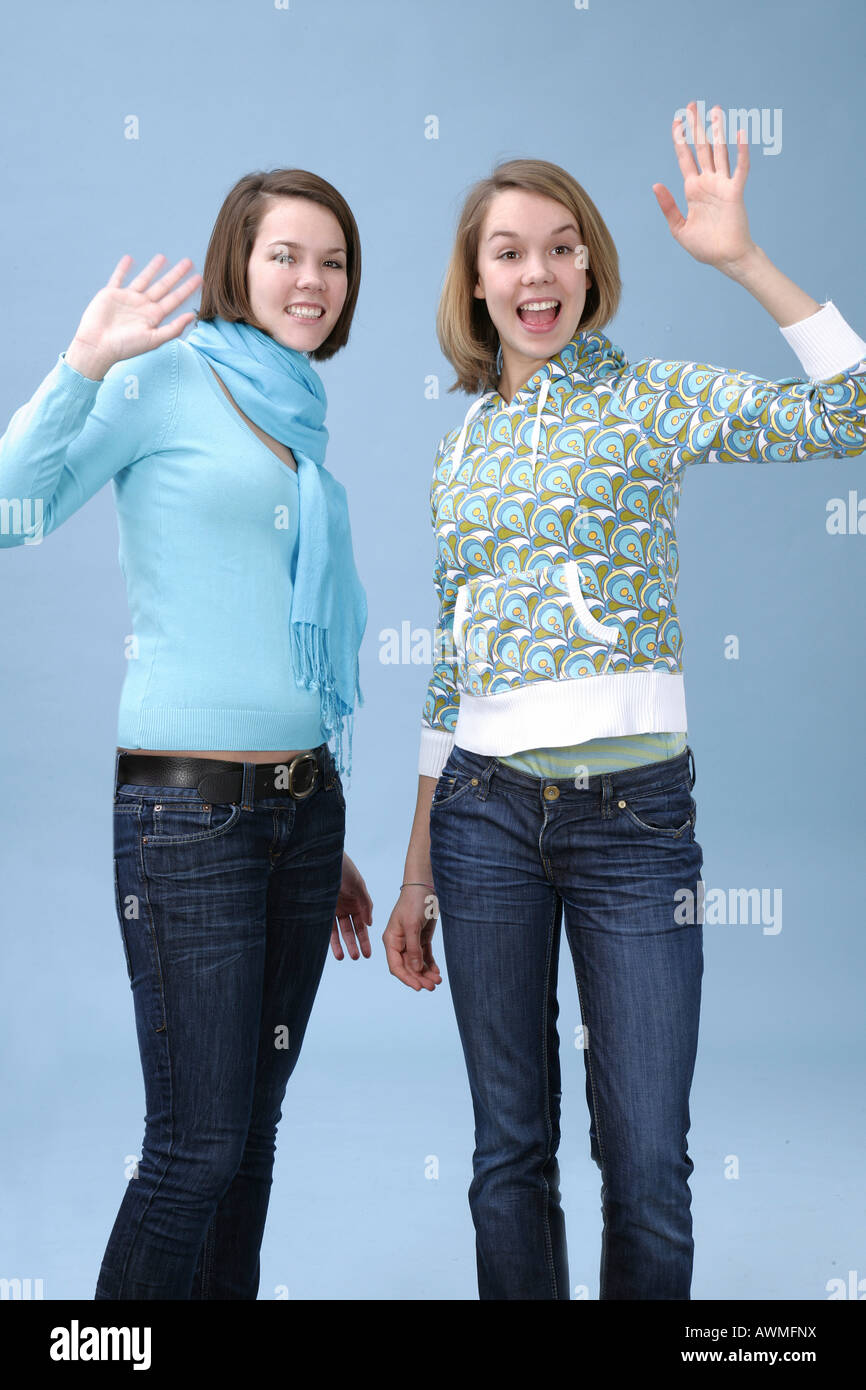 Two girls wearing casual outfits waving while strolling Stock Photo - Alamy