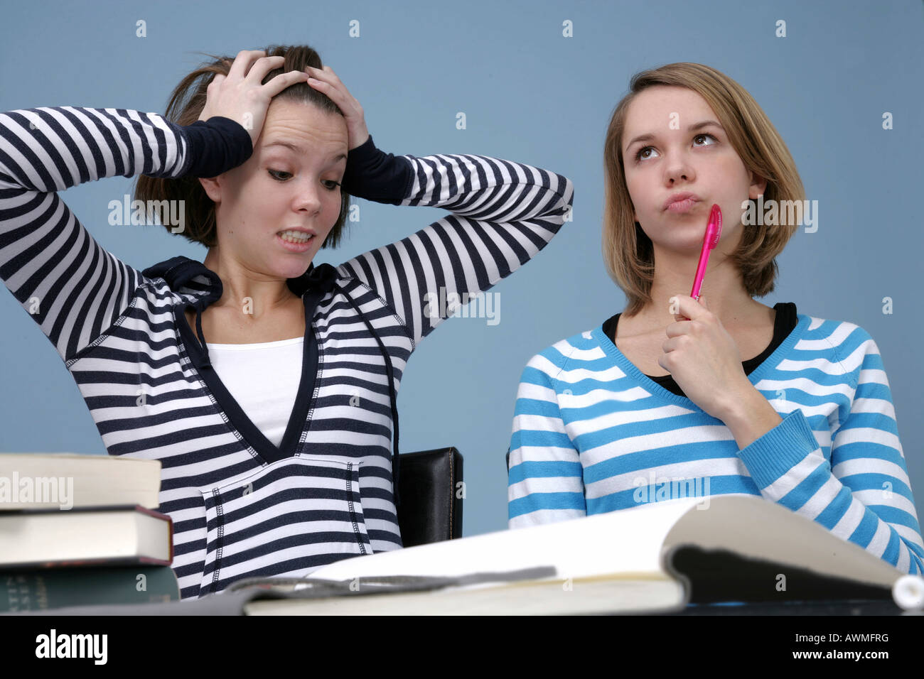 Two girls annoyed while doing their homework together Stock Photo - Alamy