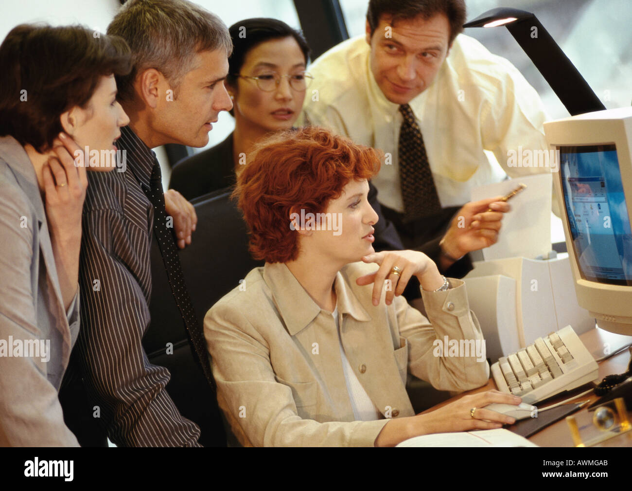 Five business people grouped around computer screen Stock Photo - Alamy