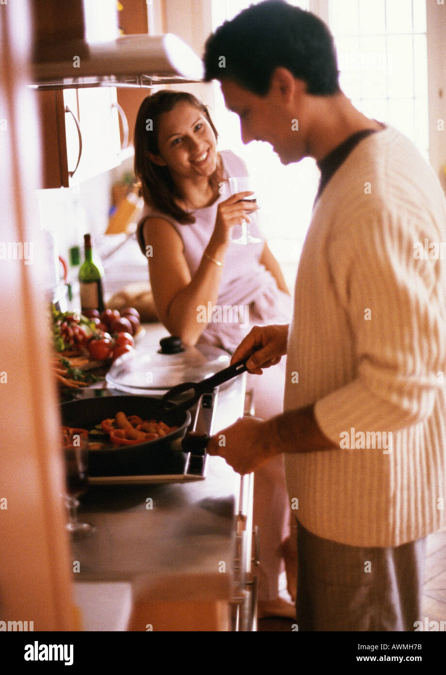 Man cooking, side view, woman holding glass, smiling Stock Photo - Alamy