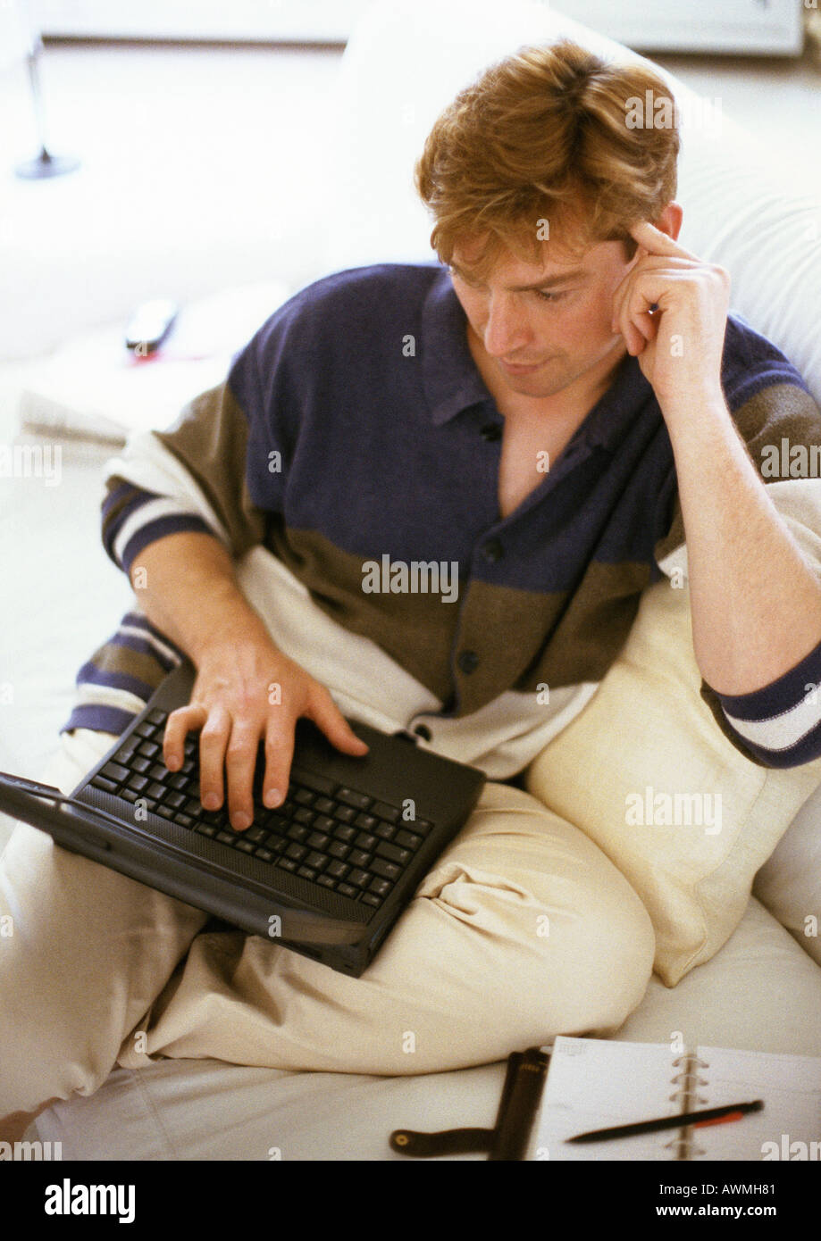 Man sitting, using laptop computer Stock Photo - Alamy