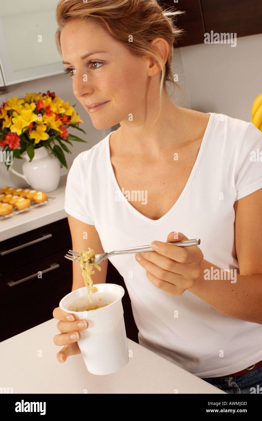 WOMAN IN KITCHEN EATING POT NOODLE Stock Photo - Alamy