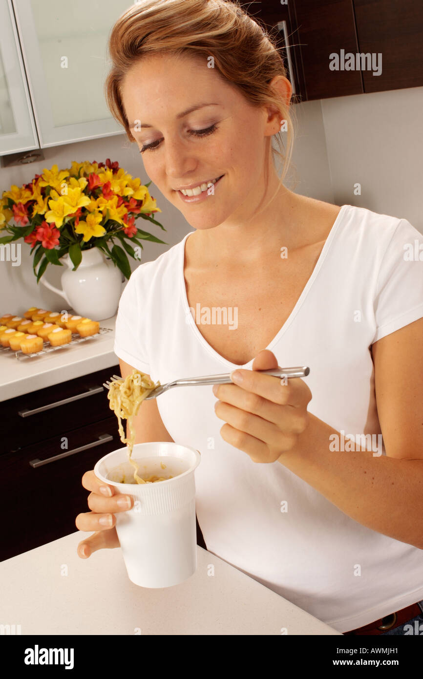 WOMAN IN KITCHEN EATING POT NOODLE Stock Photo - Alamy