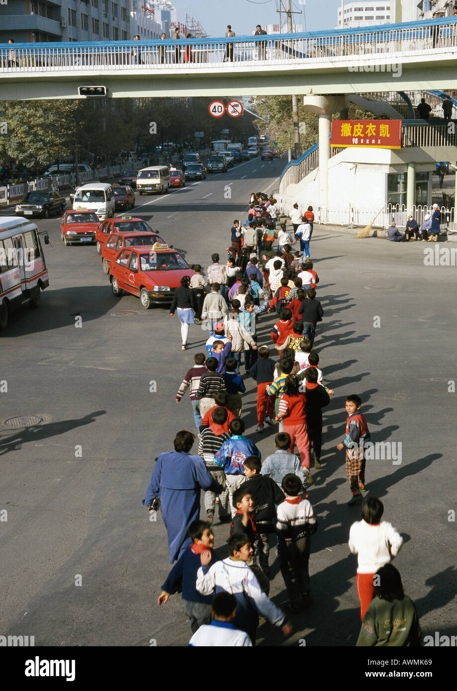 China, Xinjiang Province, Urumqi, group of children crossing street ...