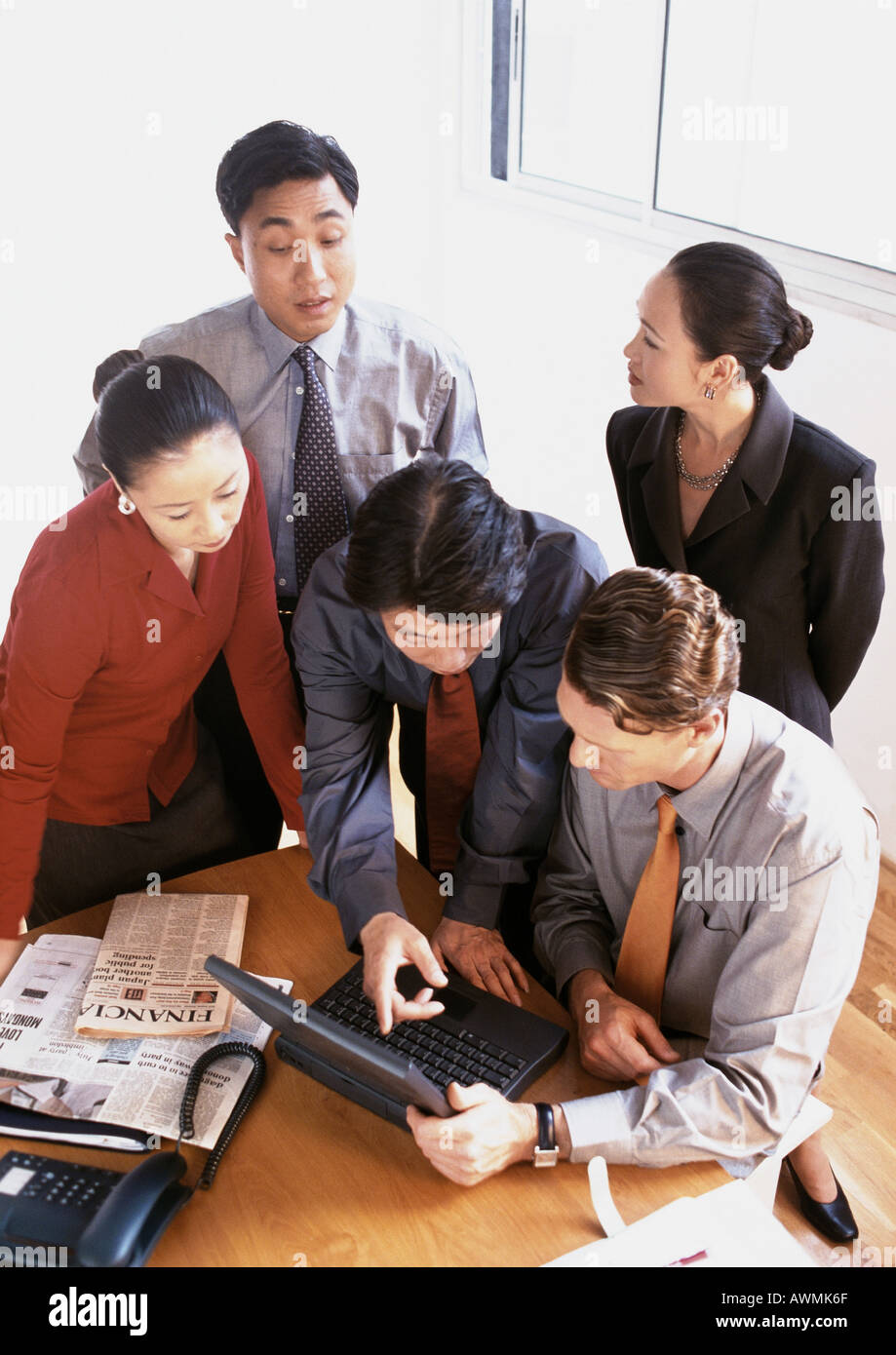 Five business associates gathered around laptop computer on table, high ...