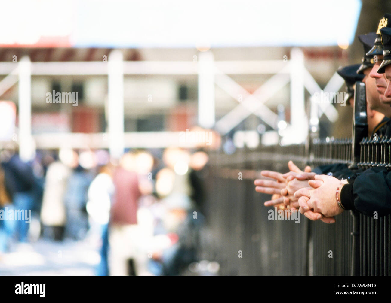 Police standing behind railings, partial side view, crowd in background ...