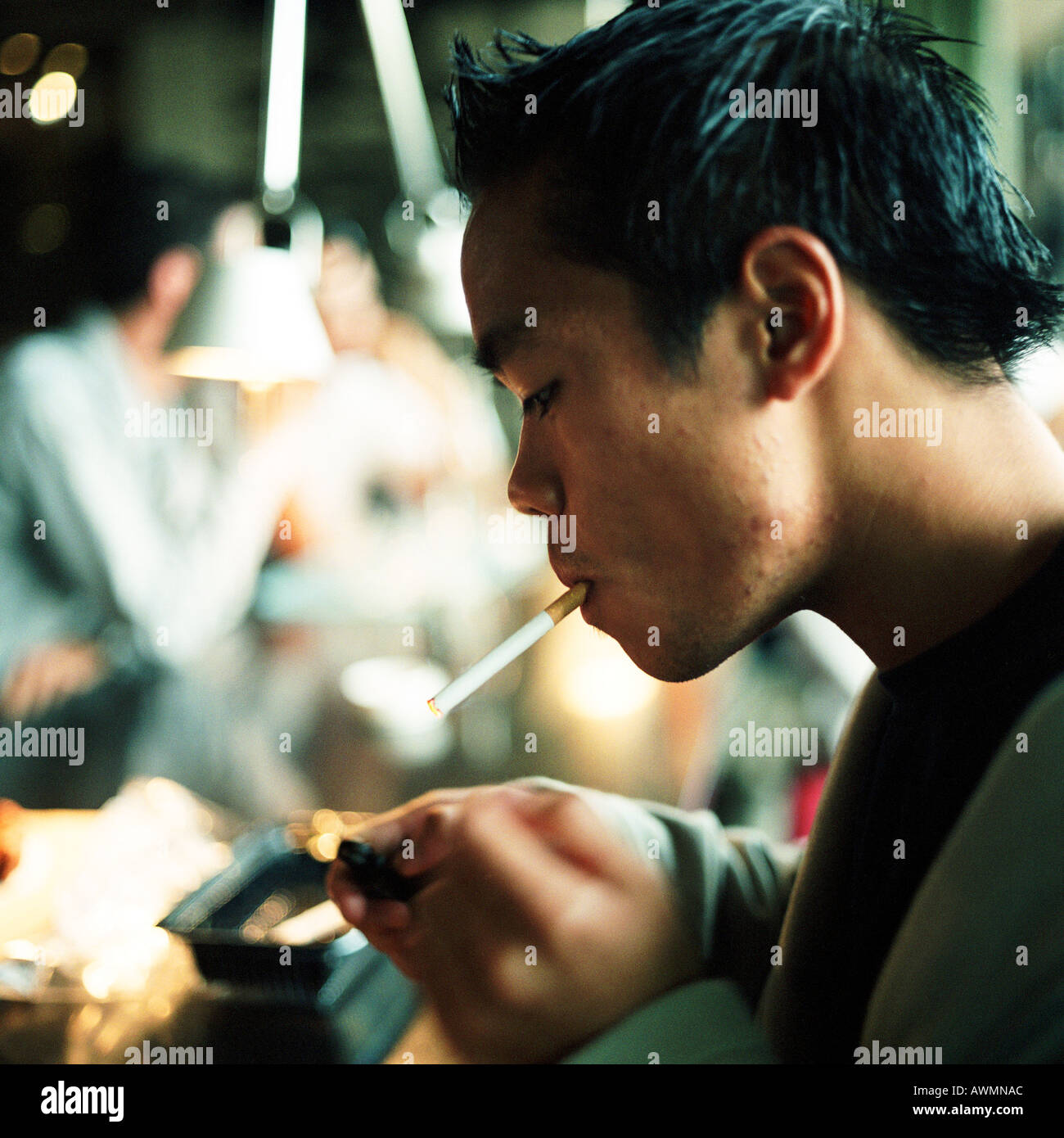 Young man lighting cigarette, side view Stock Photo - Alamy