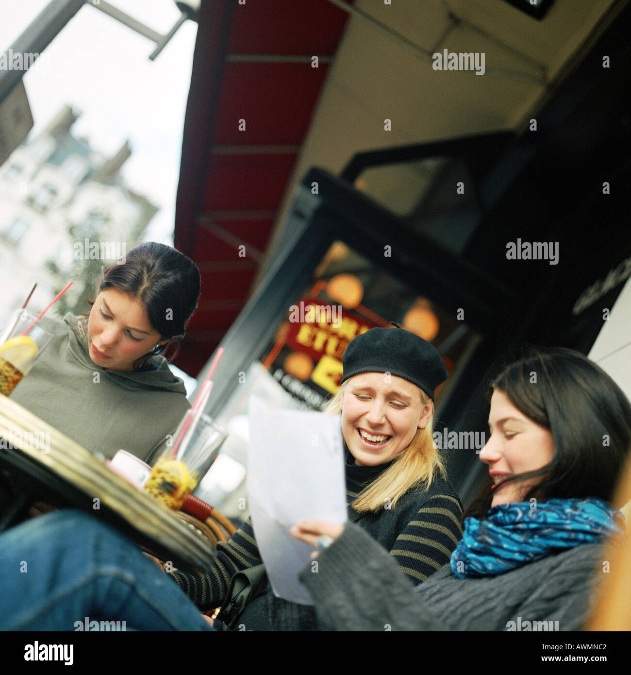 Three teenage girls sitting at cafe terrace, tilt Stock Photo - Alamy