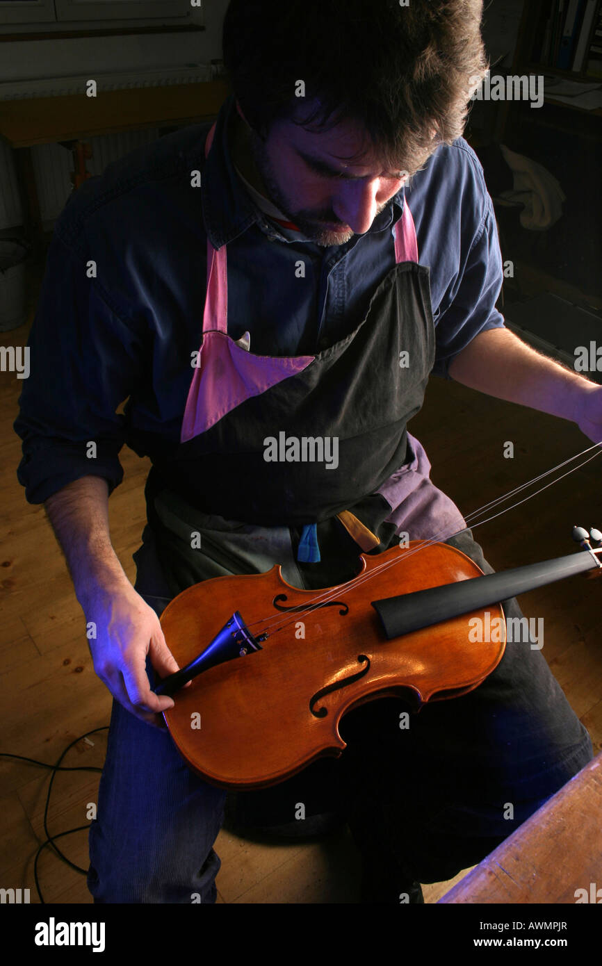 Violin-maker (luthier) stringing a violin Stock Photo - Alamy