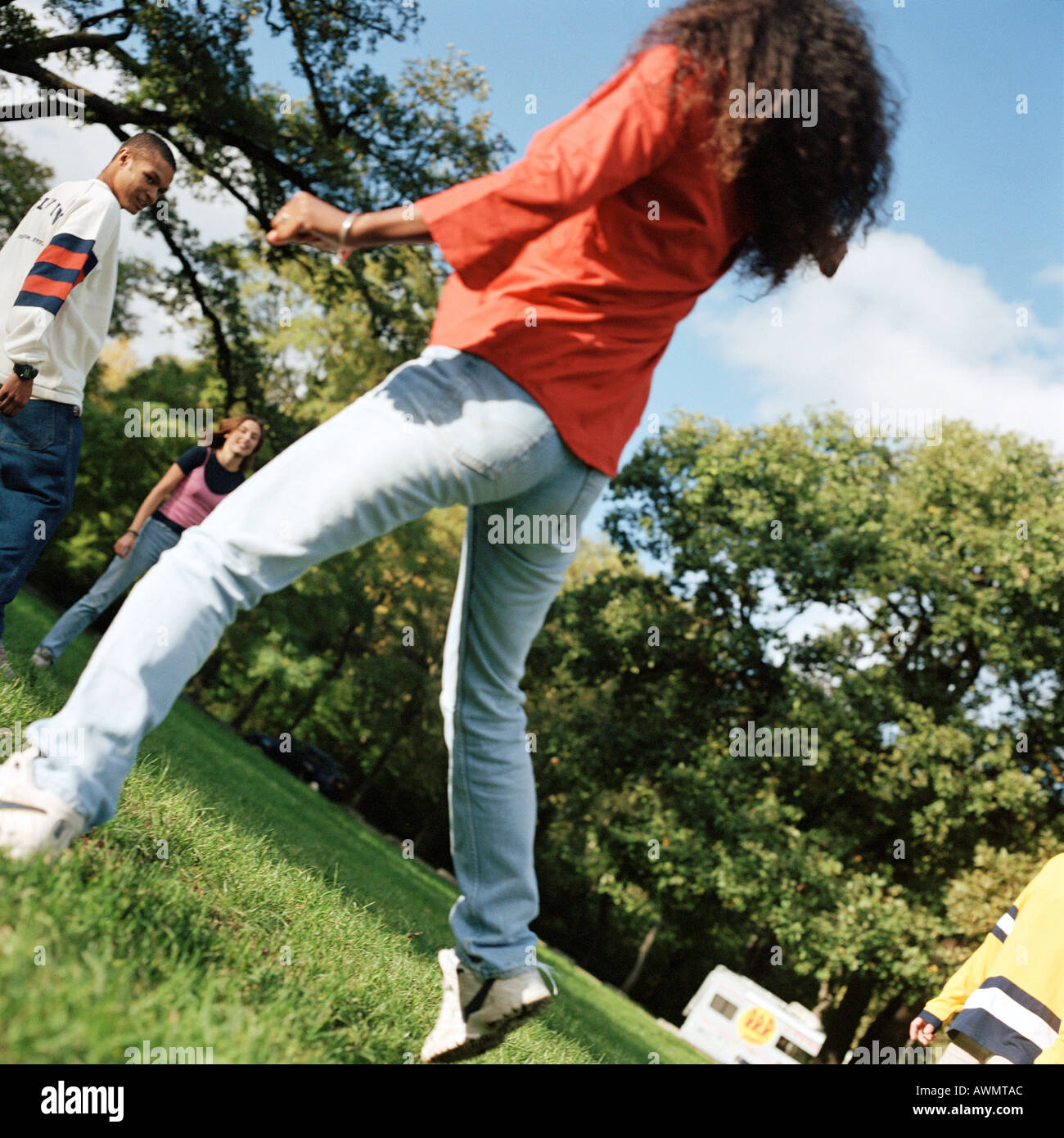 Young people together outside, young woman jumping in foreground, rear ...