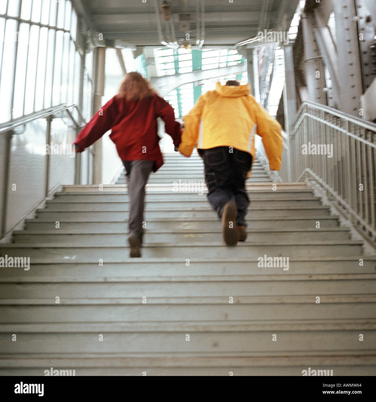 Young people holding hands and walking up stairs in elevated subway ...