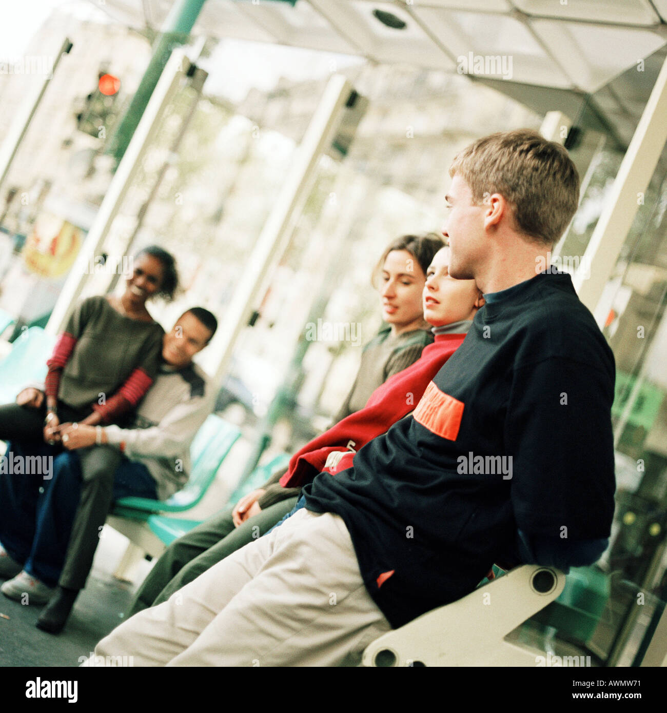 Young people sitting in bus station Stock Photo - Alamy