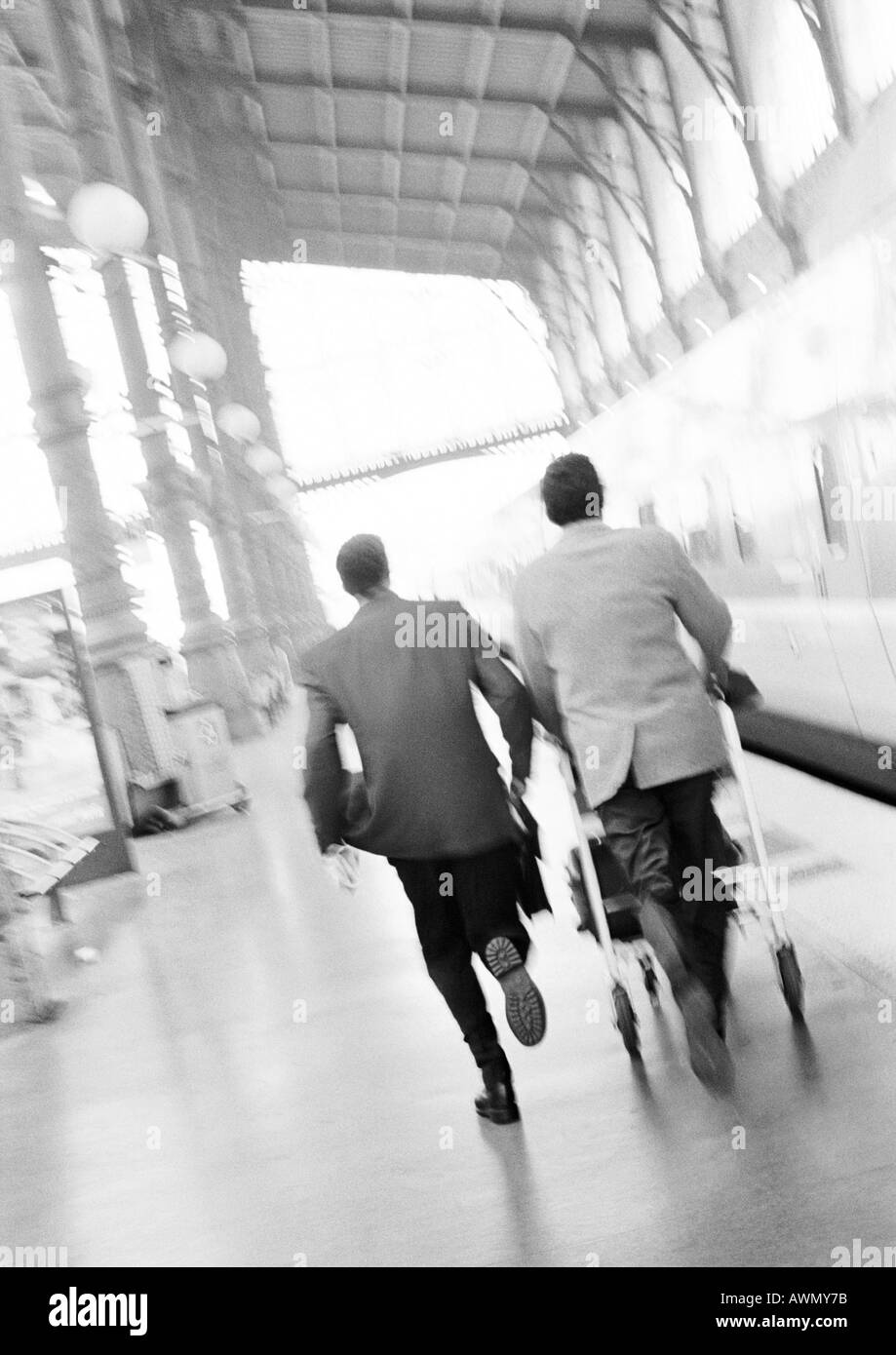 Businessmen hurrying on train platform, blurred, rear view Stock Photo ...