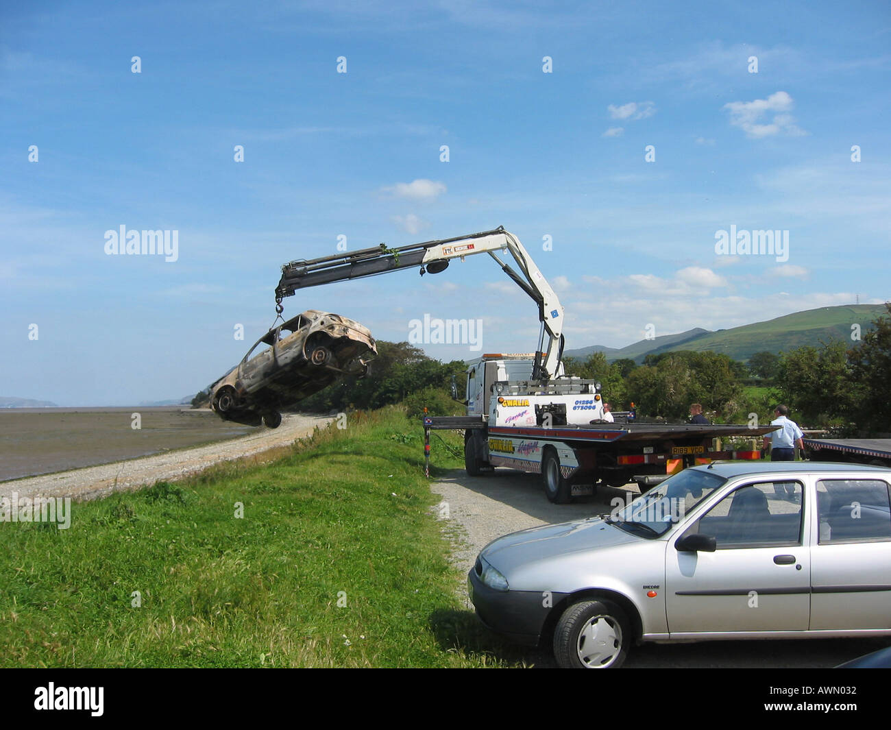Burnt out car abandoned on welsh beach being removed by crane Stock ...