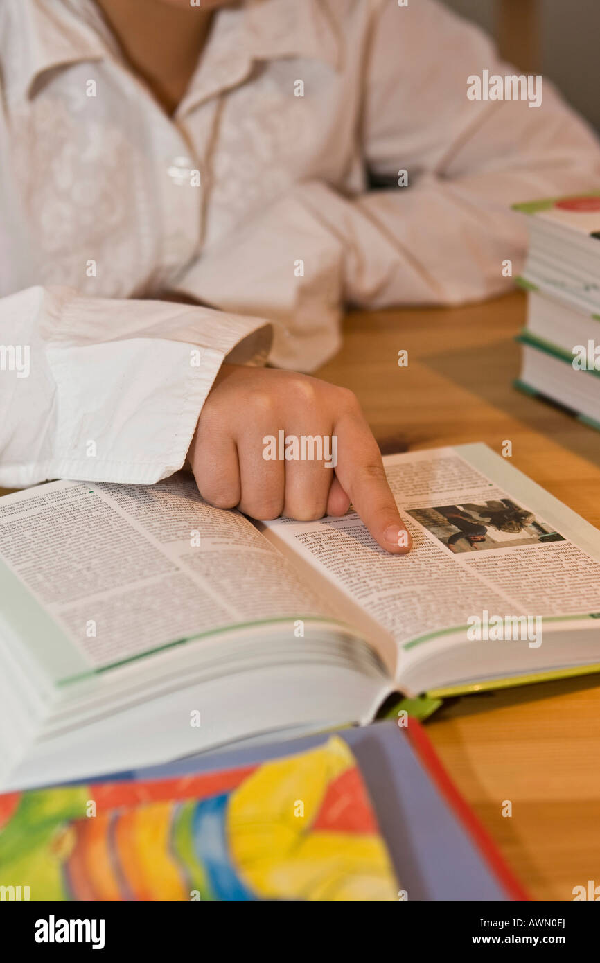Young schoolgirl doing homework in nursery, reading book Stock Photo ...