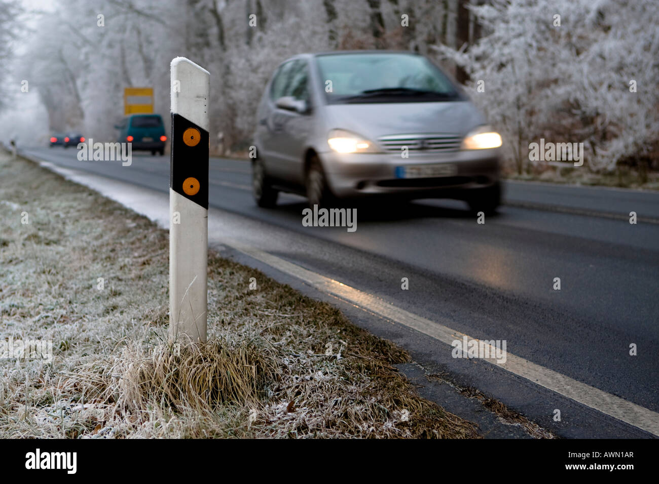 Winter traffic, car driving by reflector post with headlights on, Hesse ...