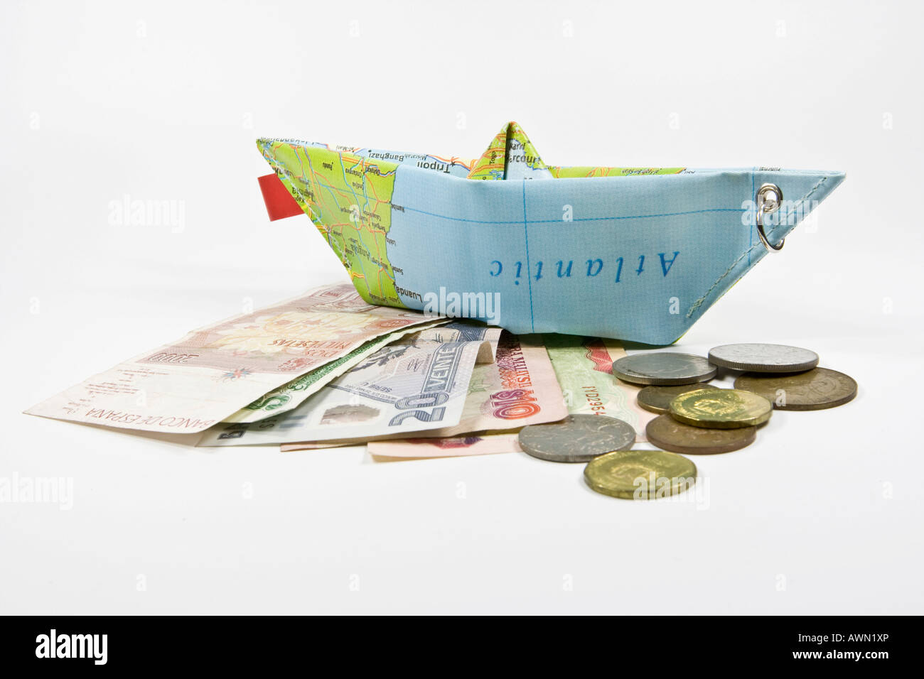 Foreign currency and a paper ship made from a map: symbol for ...