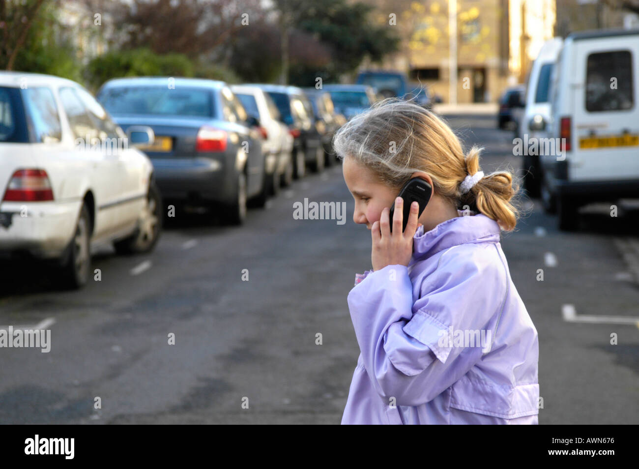 Child talking on mobile phone while crossing the road, London, England ...