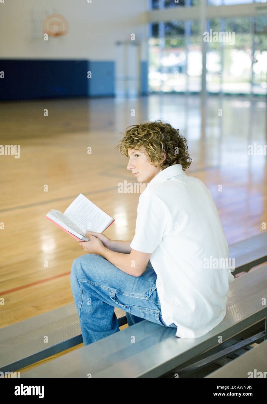 Teen boy reading book on bleachers Stock Photo - Alamy