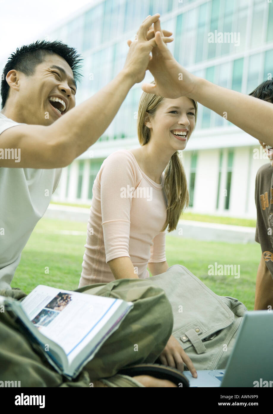 Students laughing and clasping hands on campus Stock Photo - Alamy