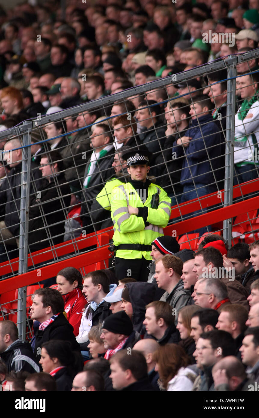 Police officer on duty standing between two sets of rival fans at a ...