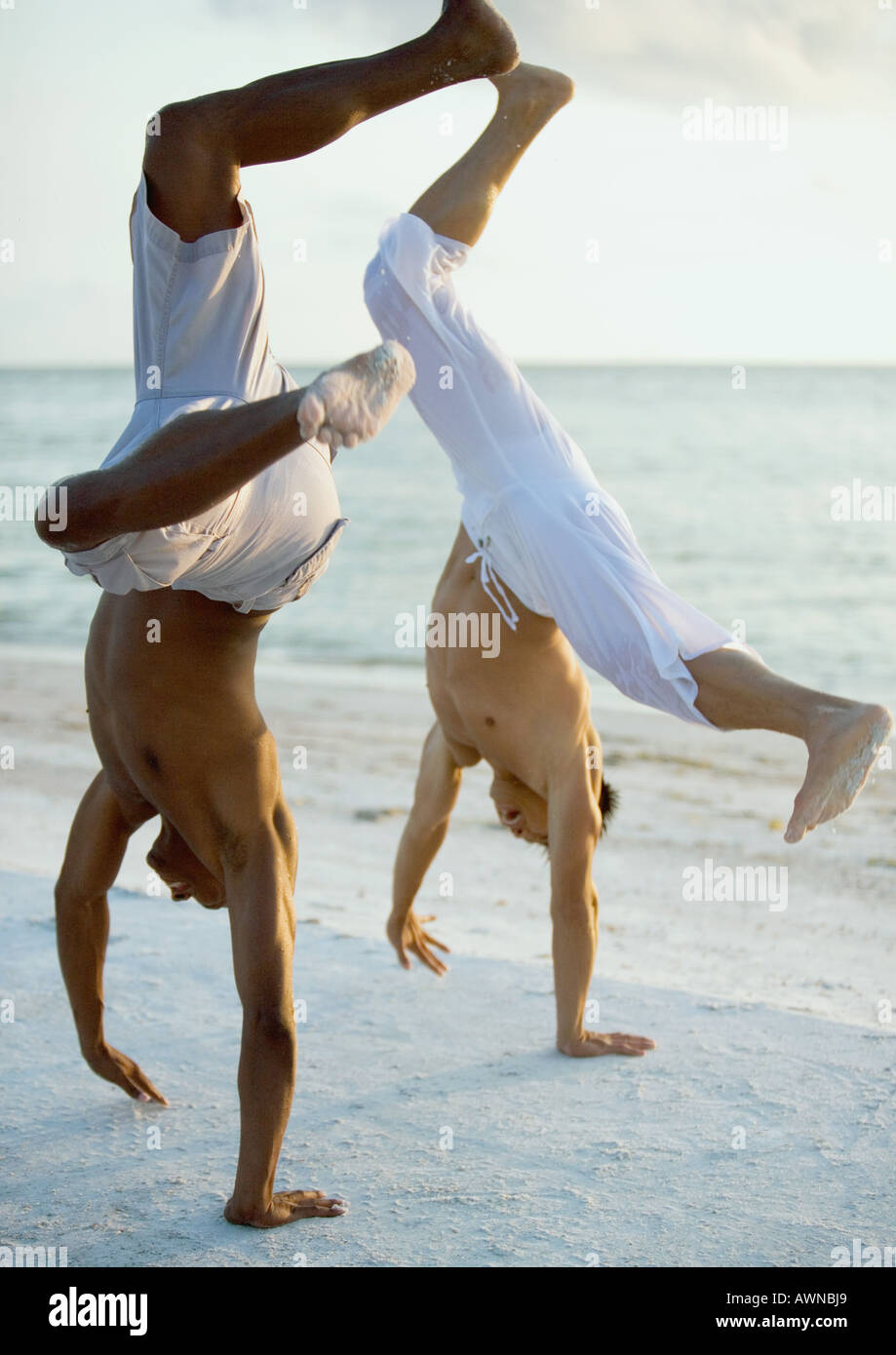 Two men turning cartwheels on beach Stock Photo - Alamy