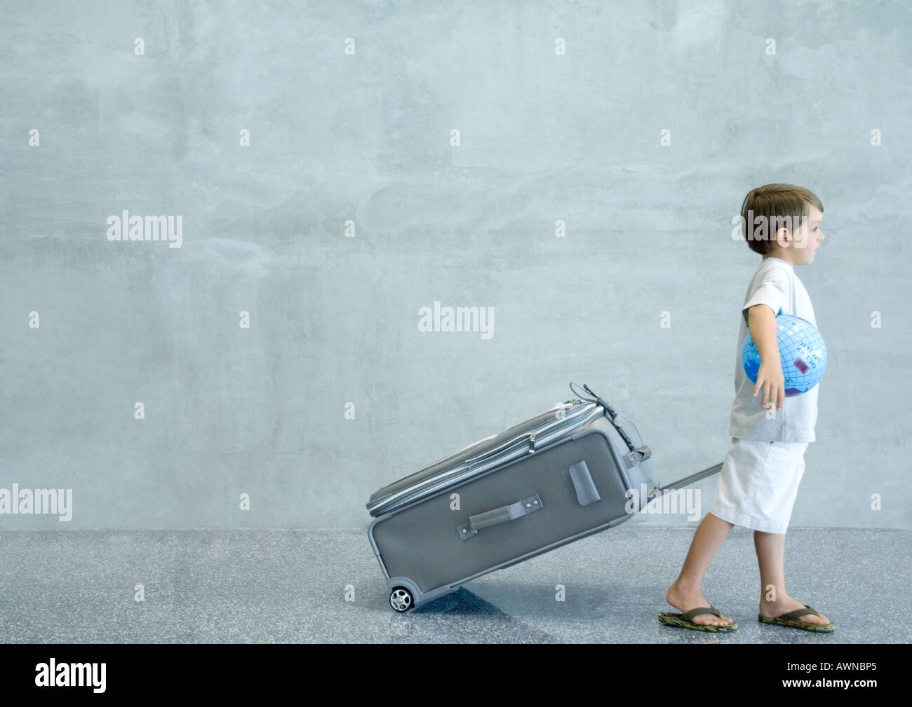 Boy pulling suitcase and carrying globe under arm Stock Photo - Alamy