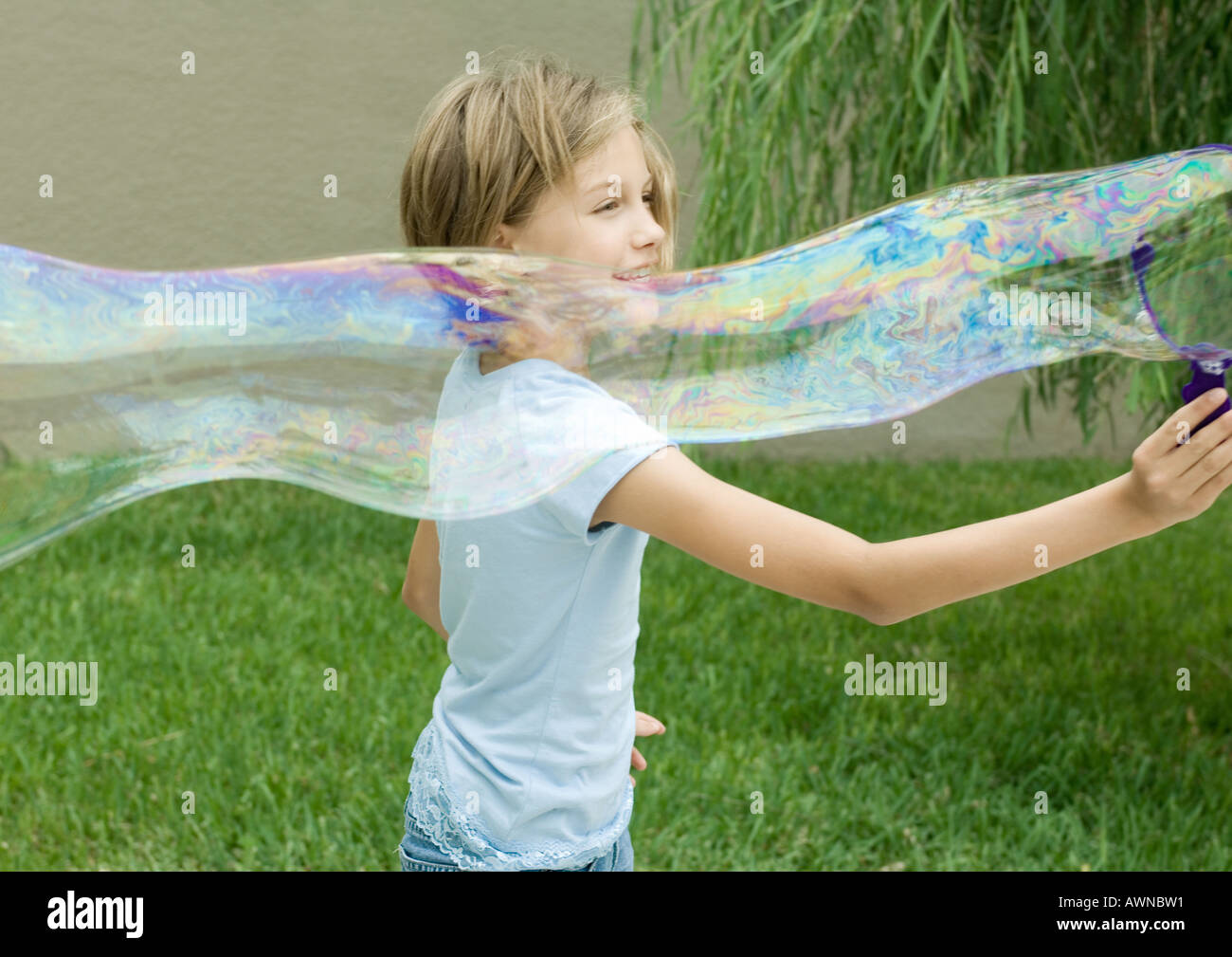 Girl making long bubble with bubble wand Stock Photo - Alamy