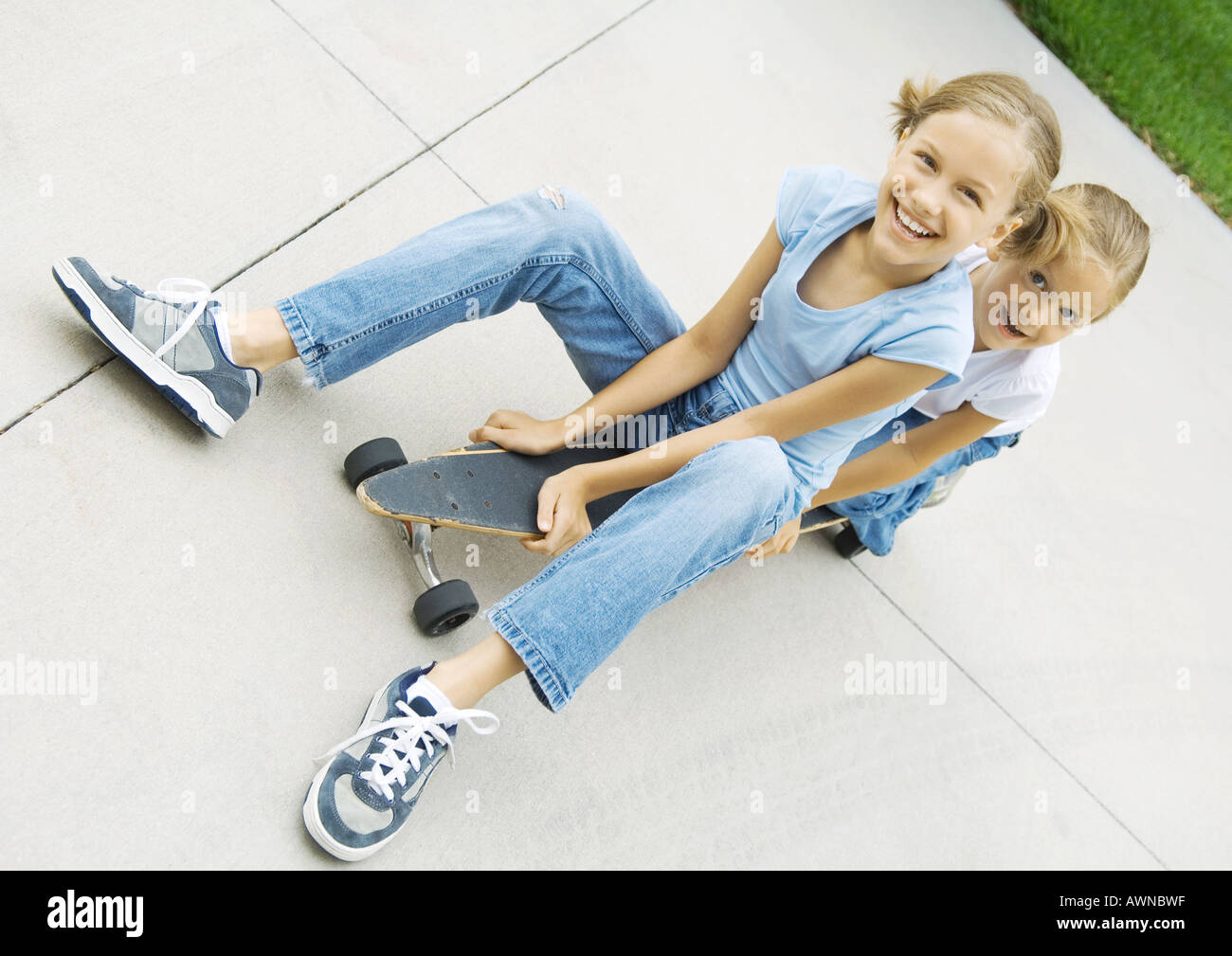 Two girls sitting on skateboard together Stock Photo - Alamy