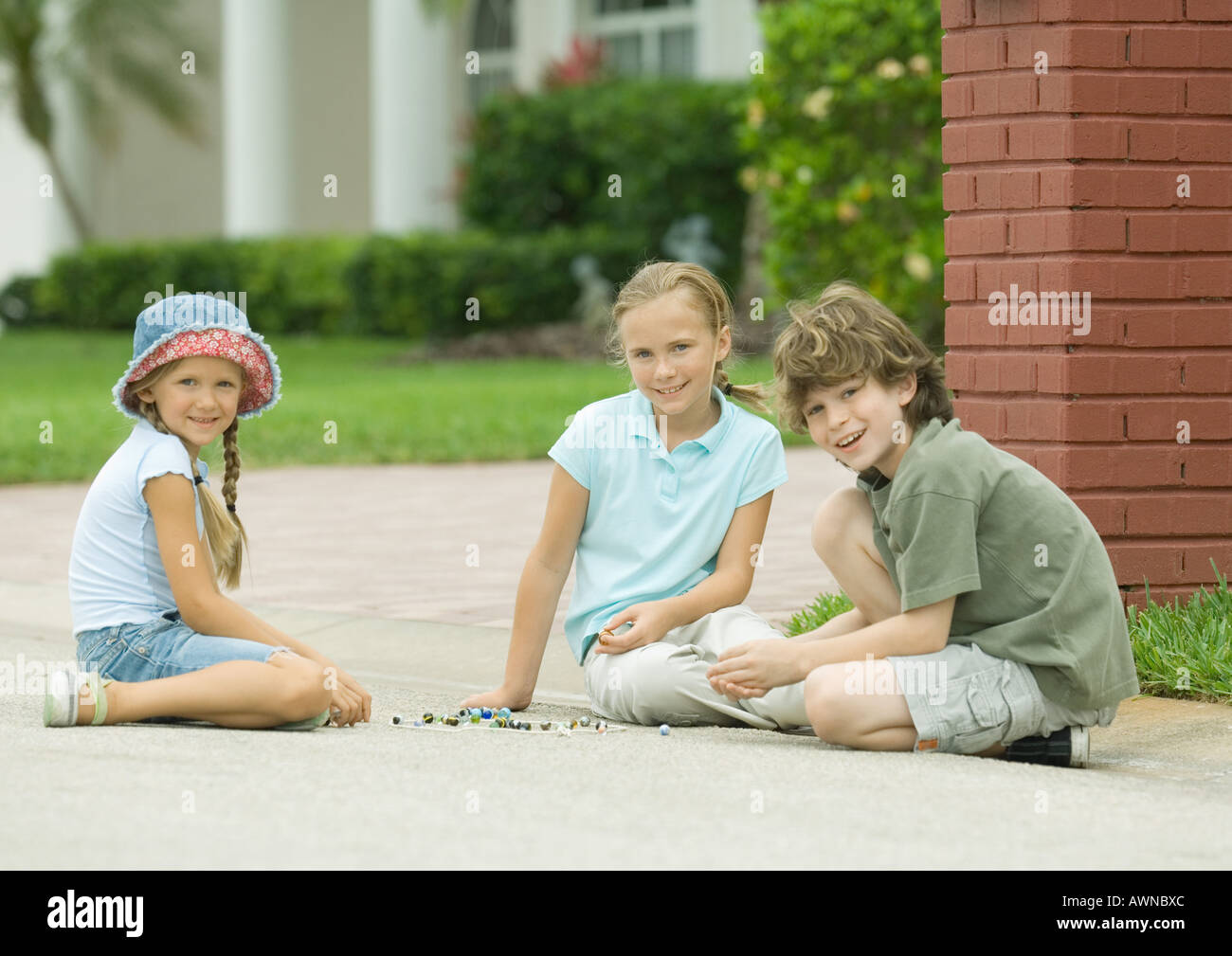 Three children playing marbles outdoors Stock Photo - Alamy