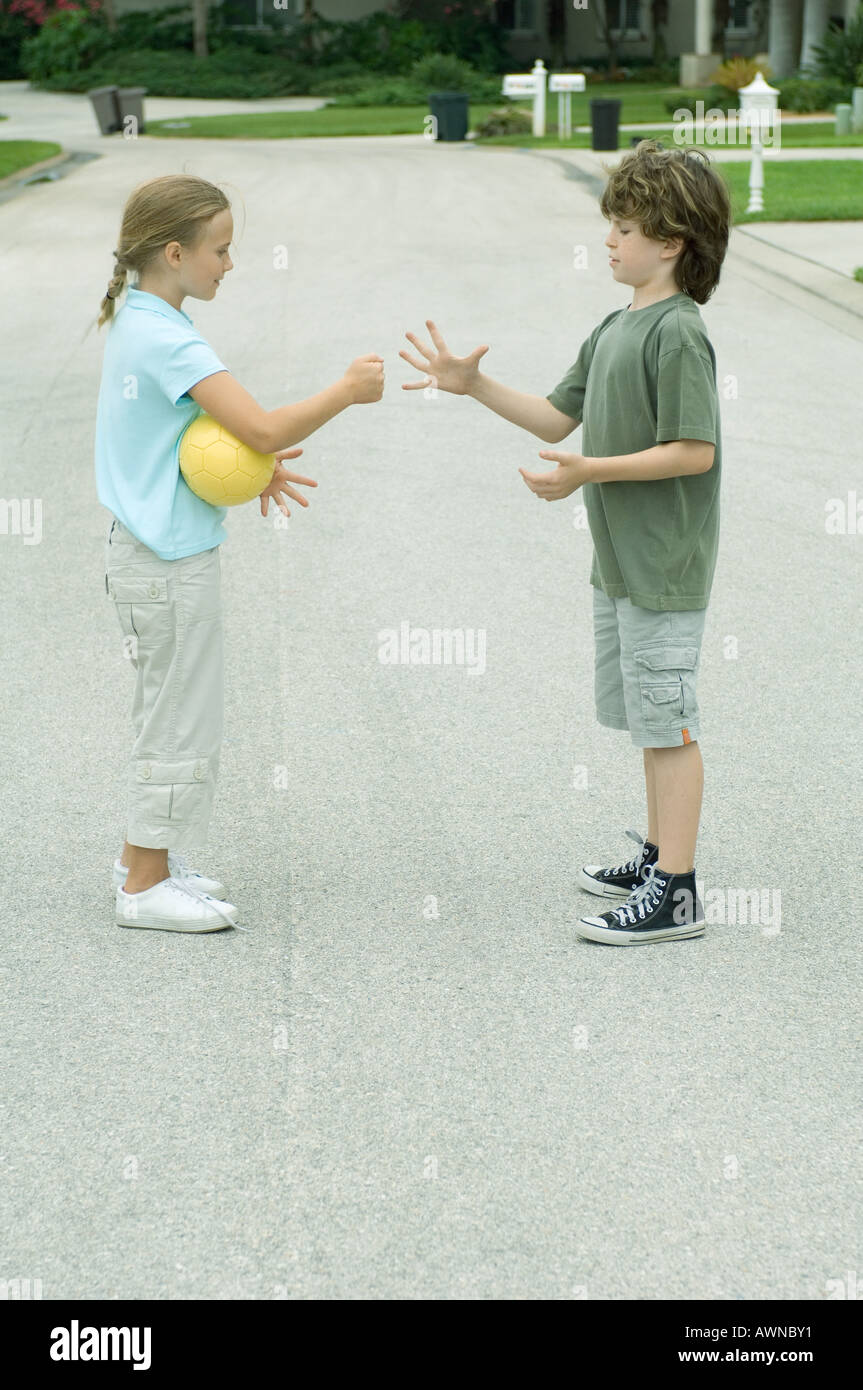 Boy and girl playing rock paper scissors in residential street Stock ...