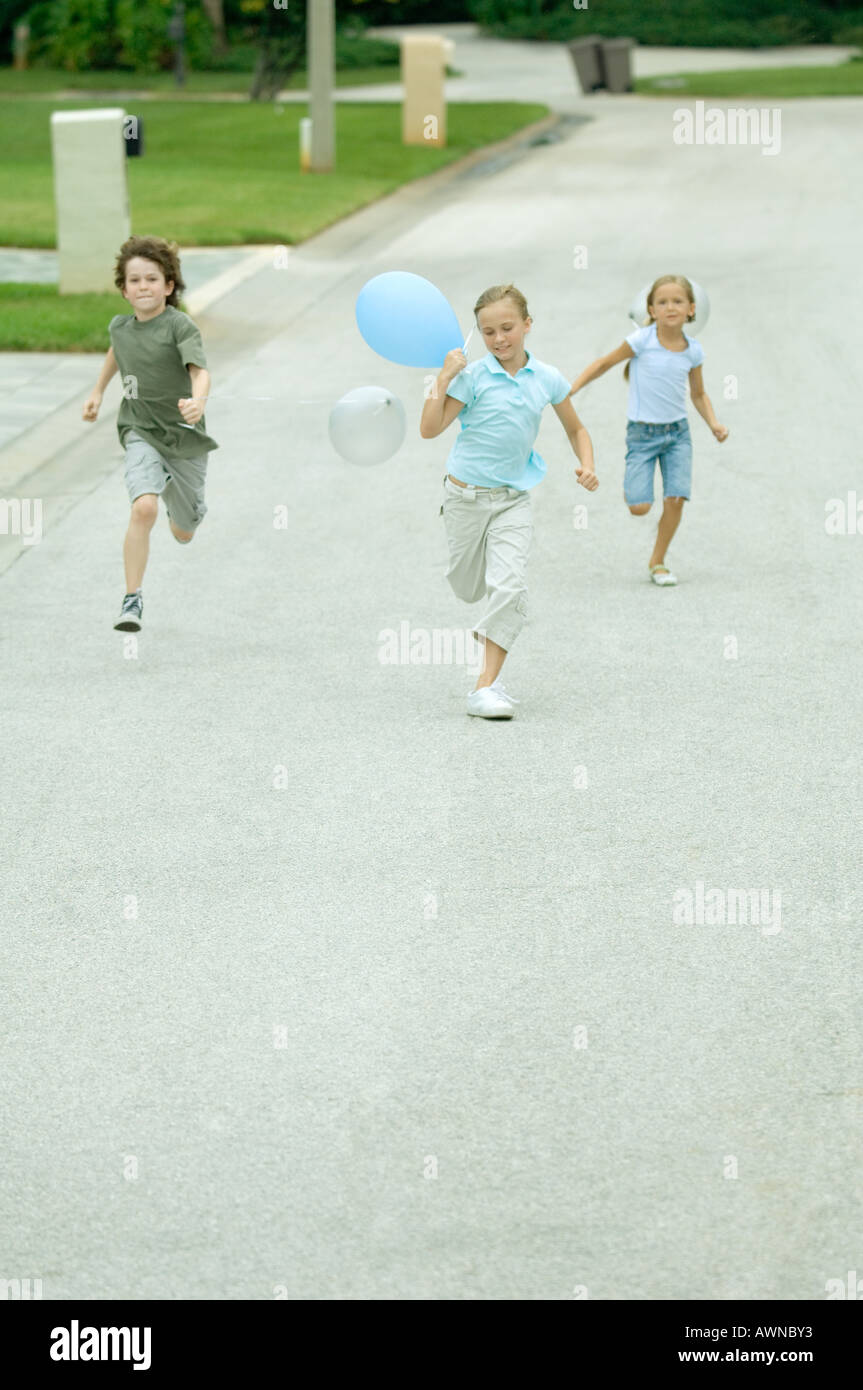 Children with balloons running through residential street Stock Photo ...