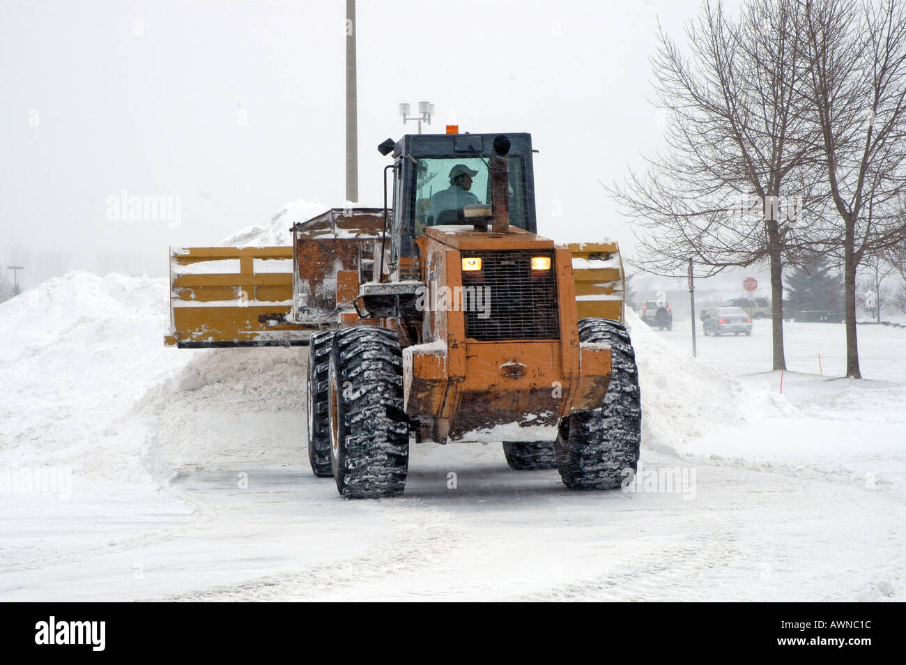 Large snow removing machinery clears shopping mall parking lot after a ...