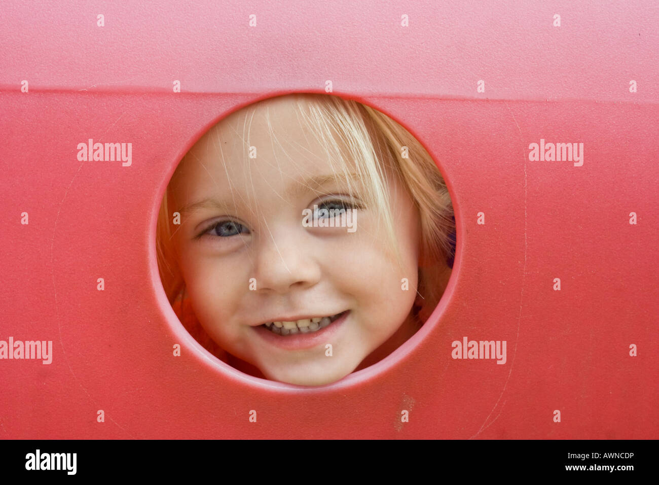 A girl peering out of a whole at the playground Stock Photo - Alamy