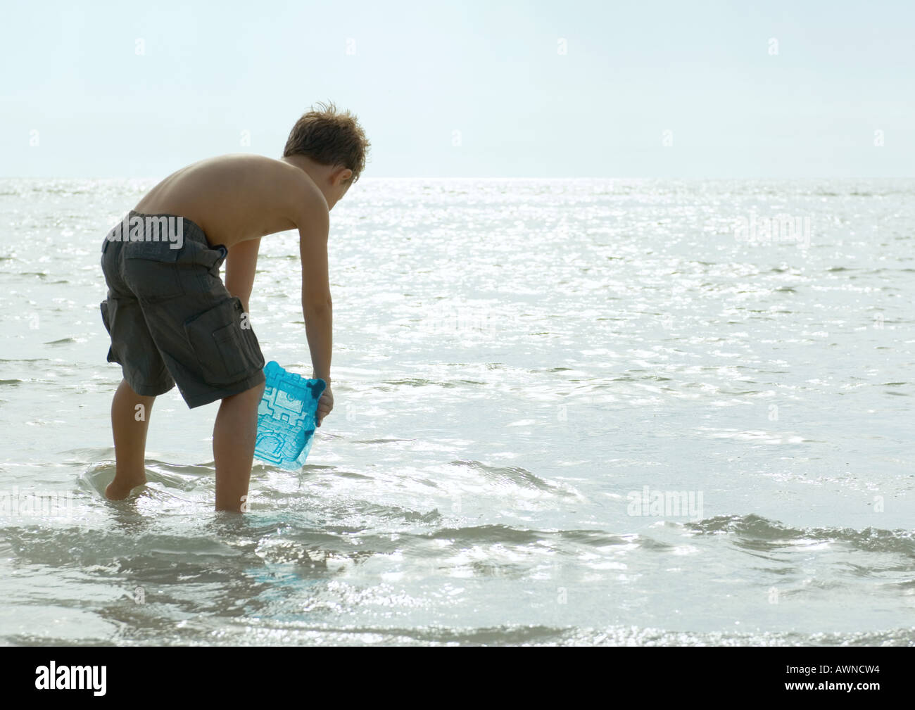 Boy filling bucket with water in surf Stock Photo - Alamy