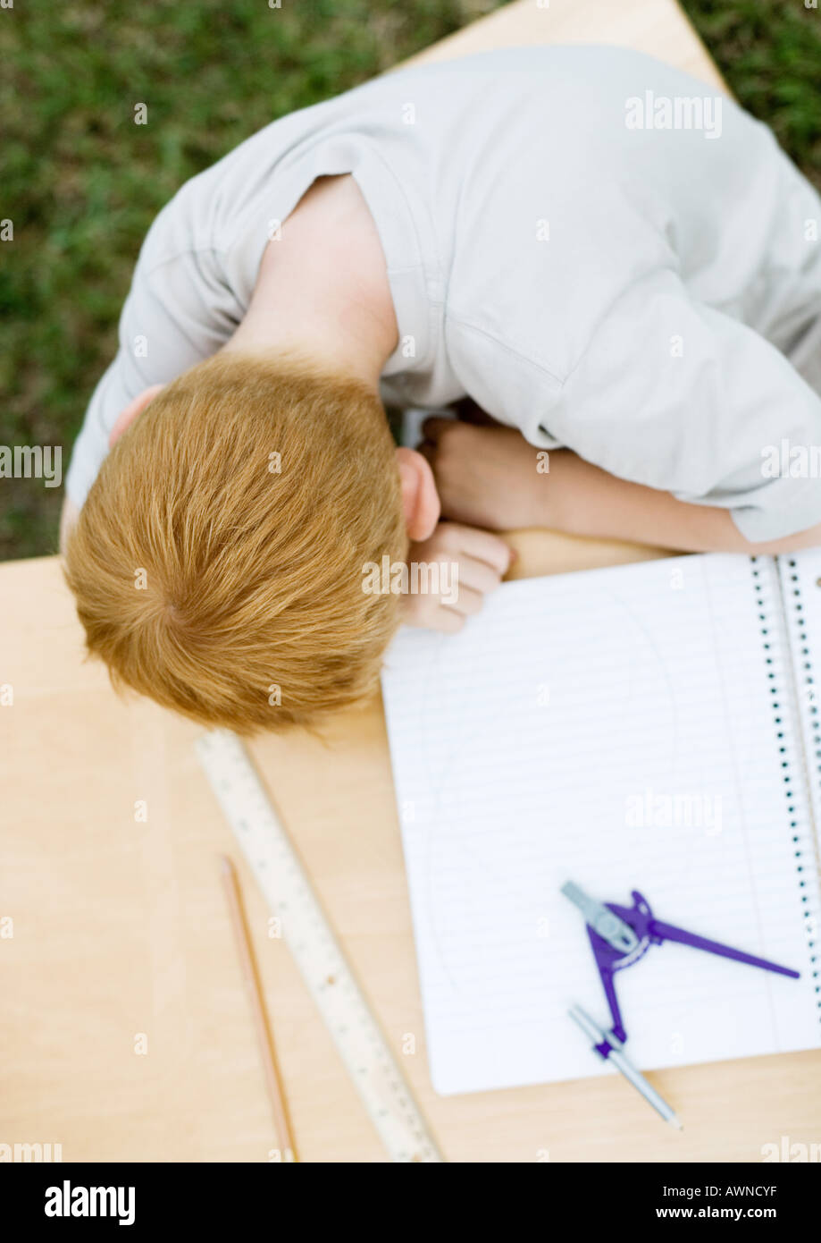 Boy with head on table next to open notebook Stock Photo - Alamy