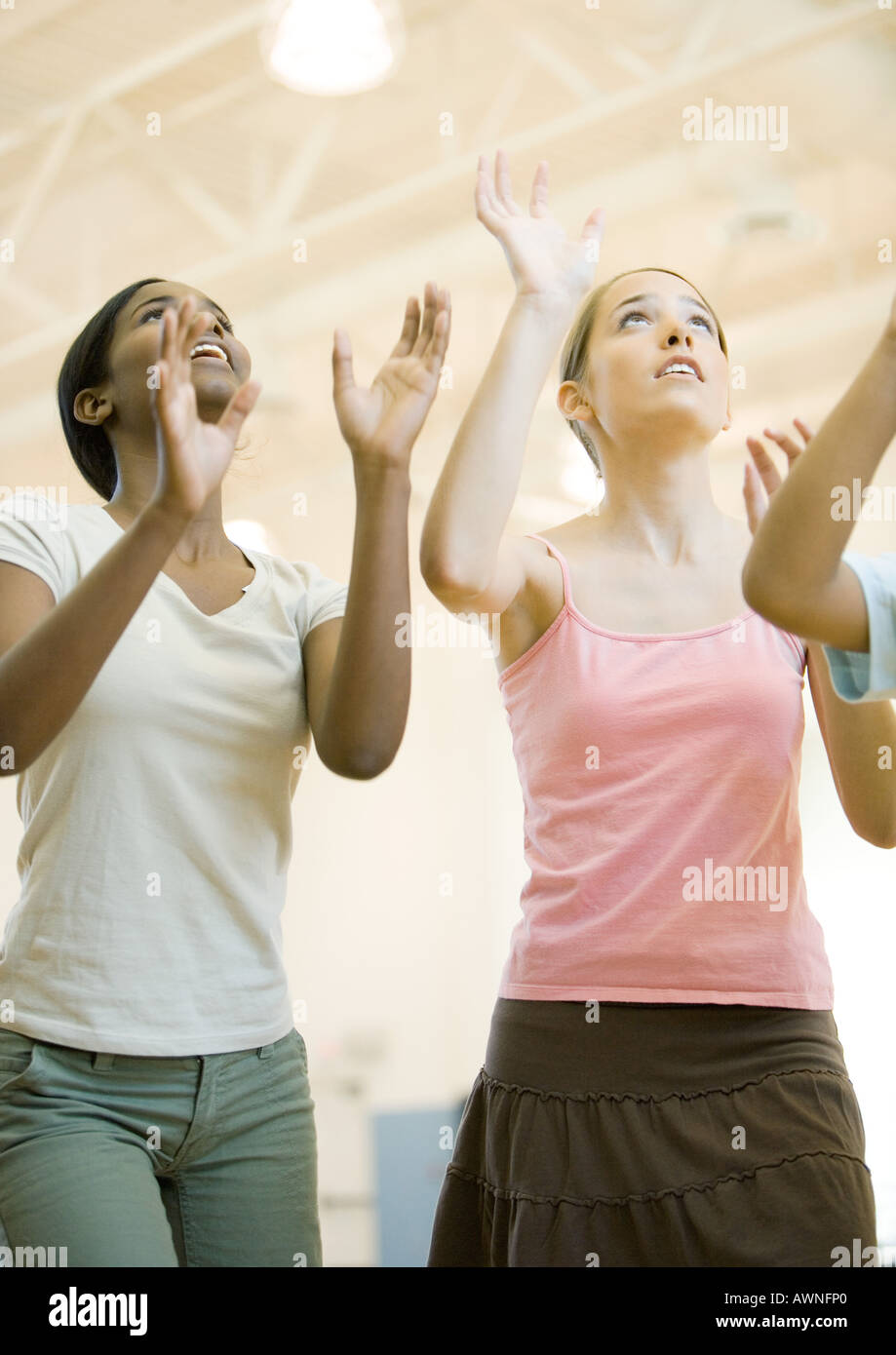 Teenage girls holding arms up to hit ball Stock Photo - Alamy