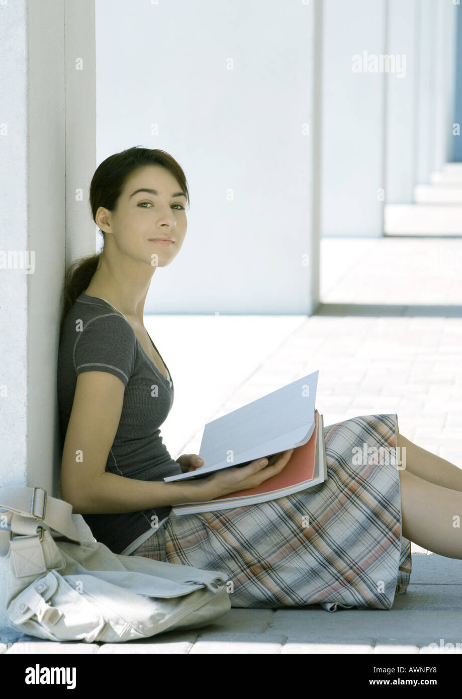 Female college student sitting on ground, studying Stock Photo - Alamy