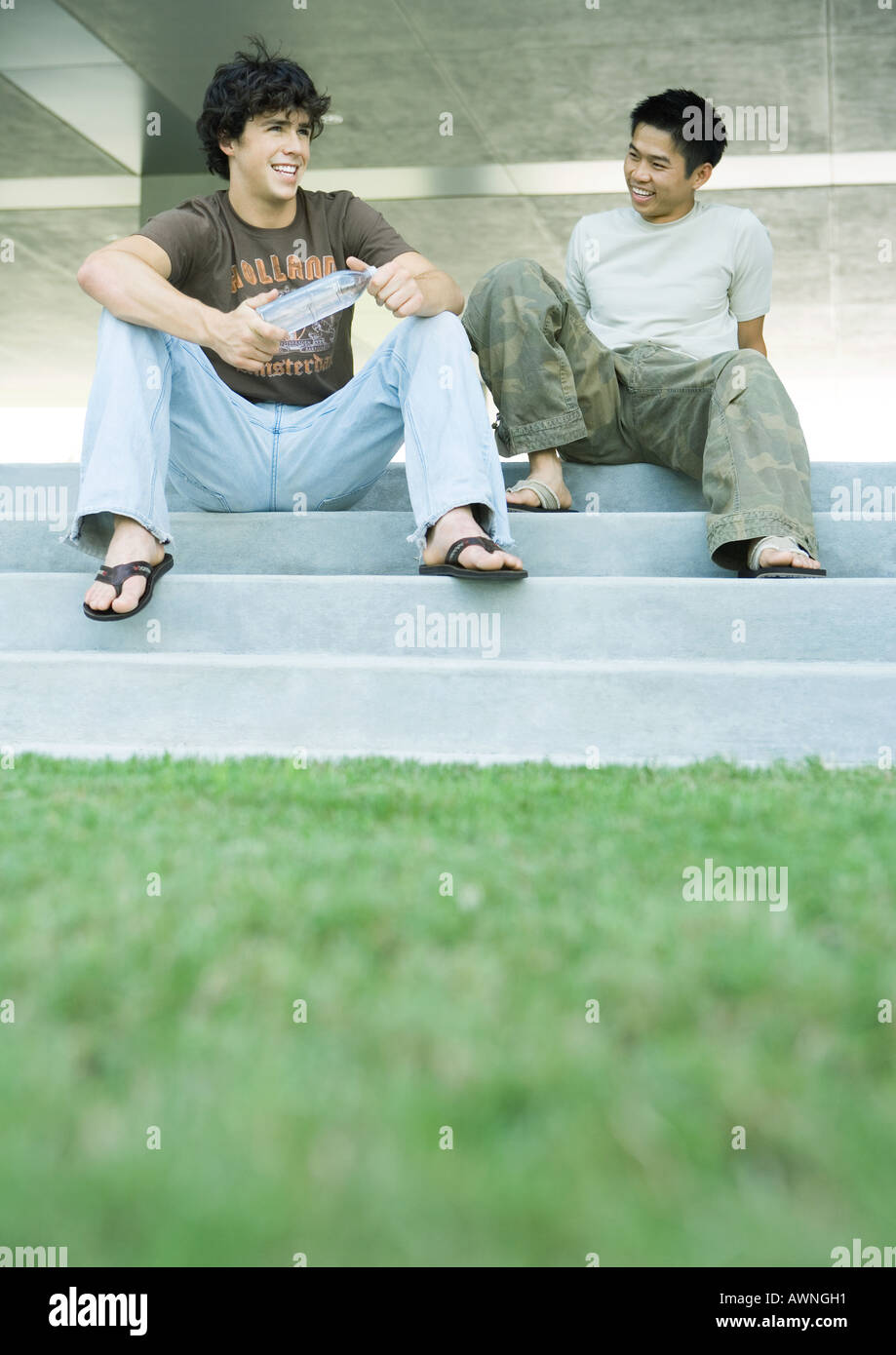 Two male college students sitting on steps together Stock Photo - Alamy
