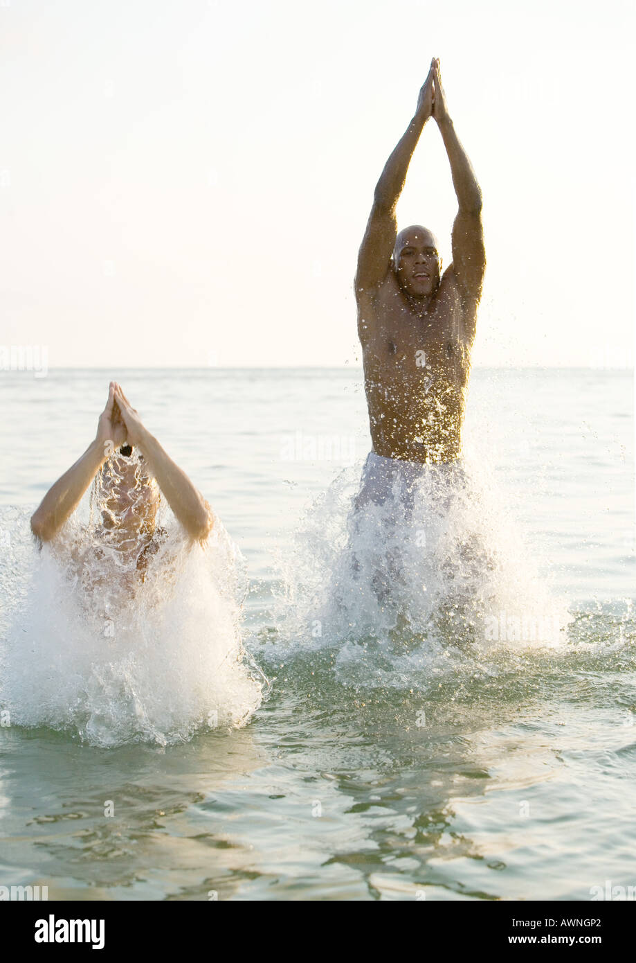 Two men emerging from water with hands over heads Stock Photo - Alamy