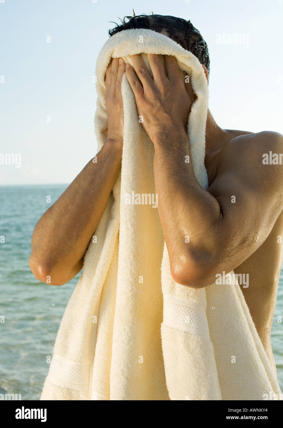Man wiping face with towel, sea in background Stock Photo - Alamy