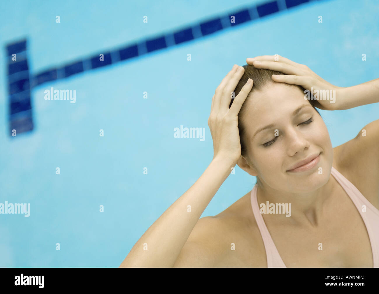 Woman smiling with hands on head, pool in background Stock Photo - Alamy